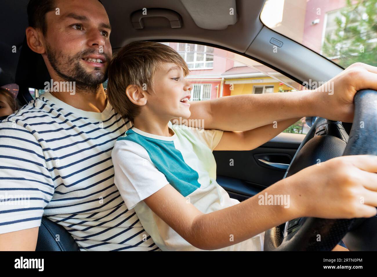 Father teaching his young son how to drive car on his lap Stock Photo ...