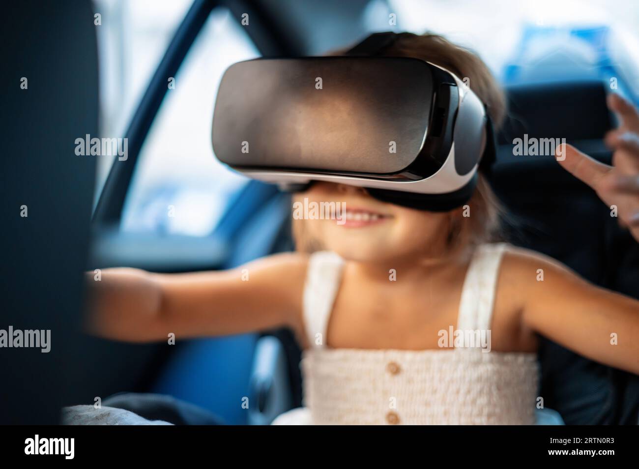 Small girl sitting in the car in VR glasses in child safety seat Stock ...