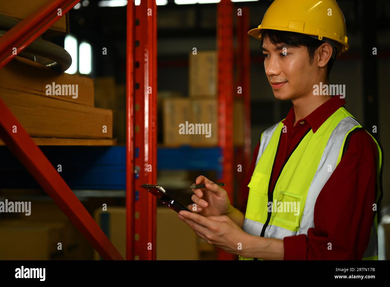 Male factory worker holding clipboard checking product material in ...