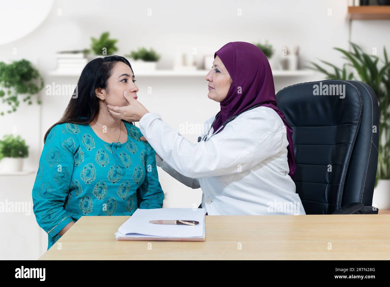 Young indian woman having her eyes examined by female muslim eye doctor ...