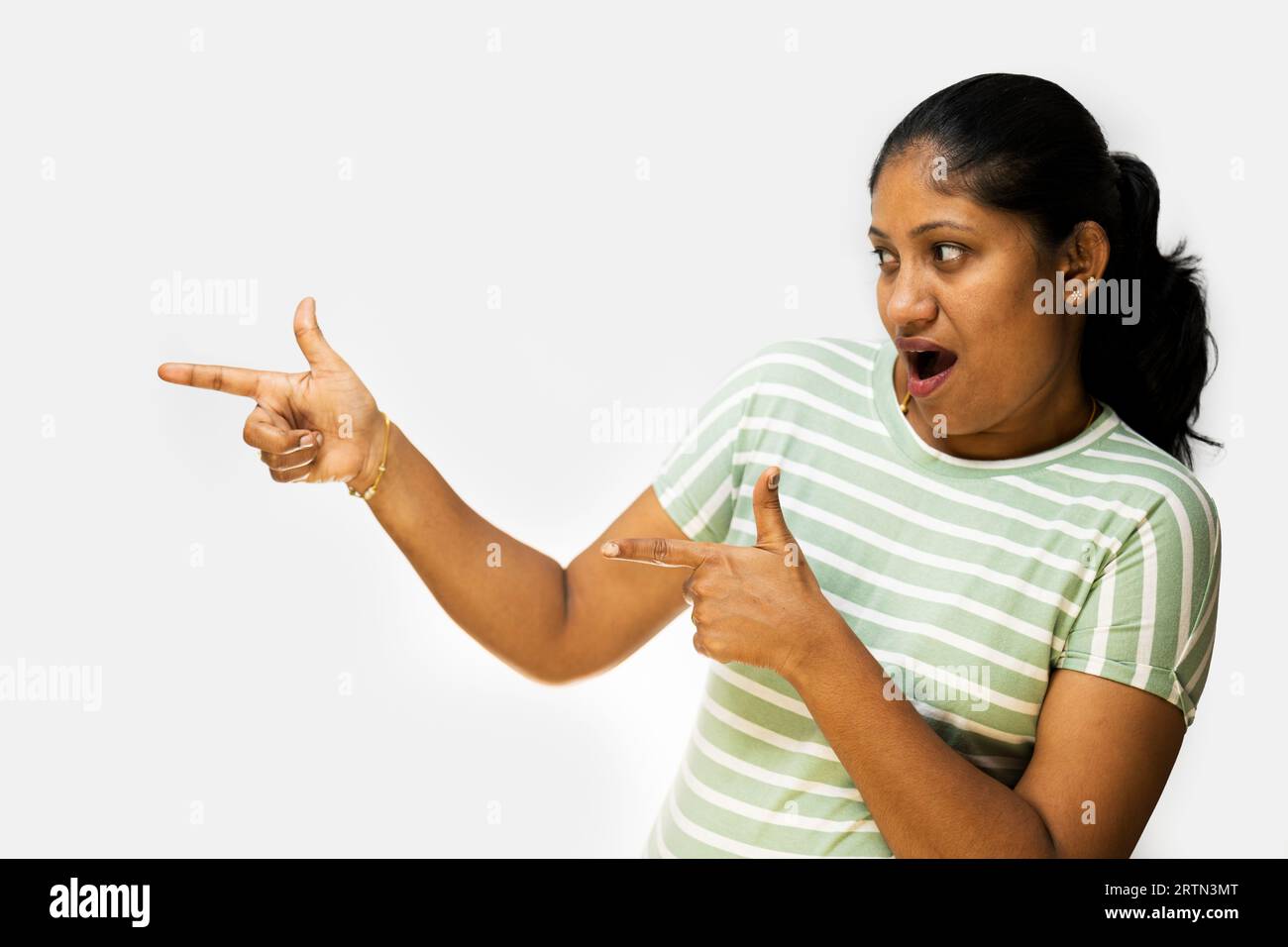 A surprised woman pointing to the side on a white background. She is ...