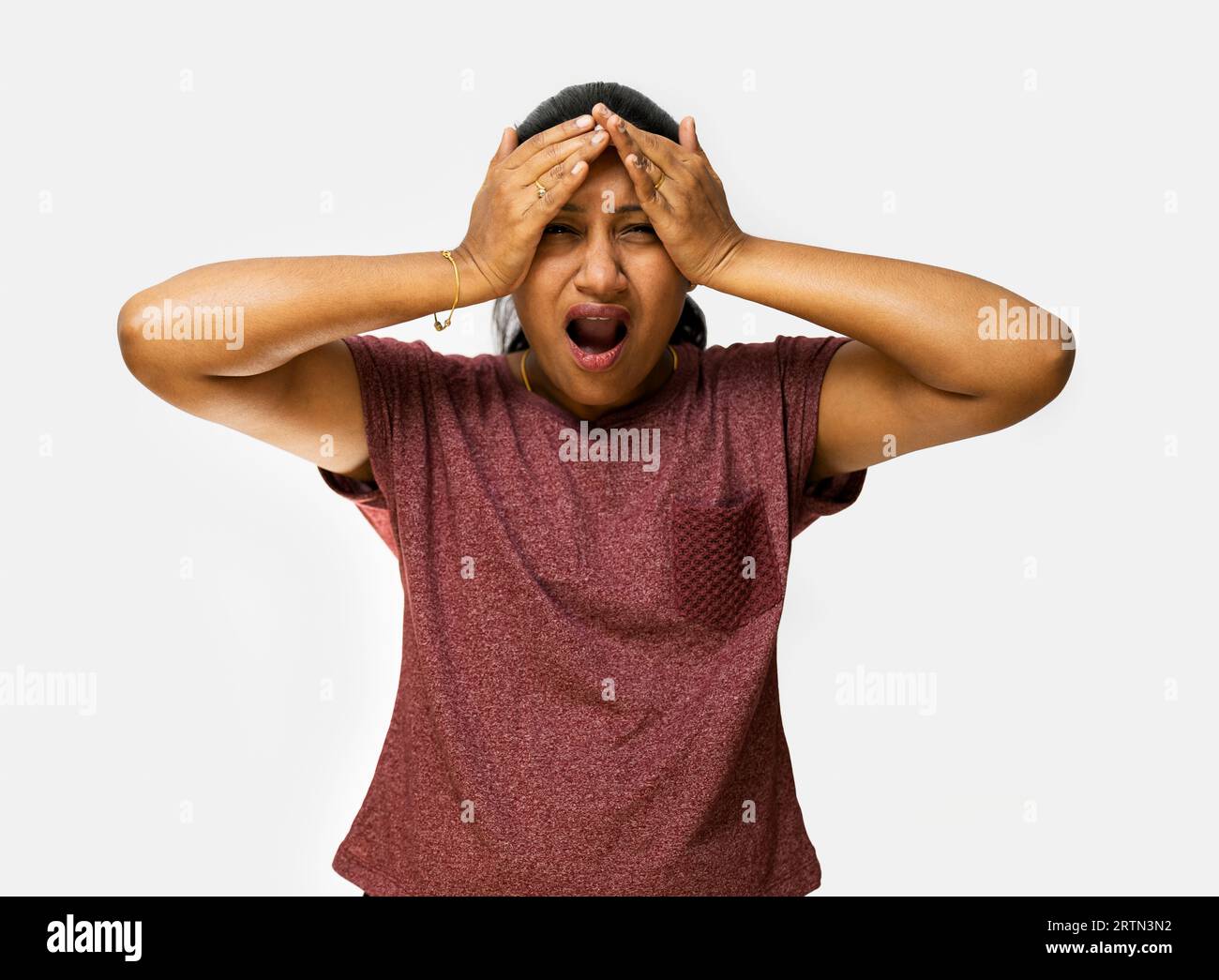 A woman is holding her head in pain, her face contorted in agony. She ...