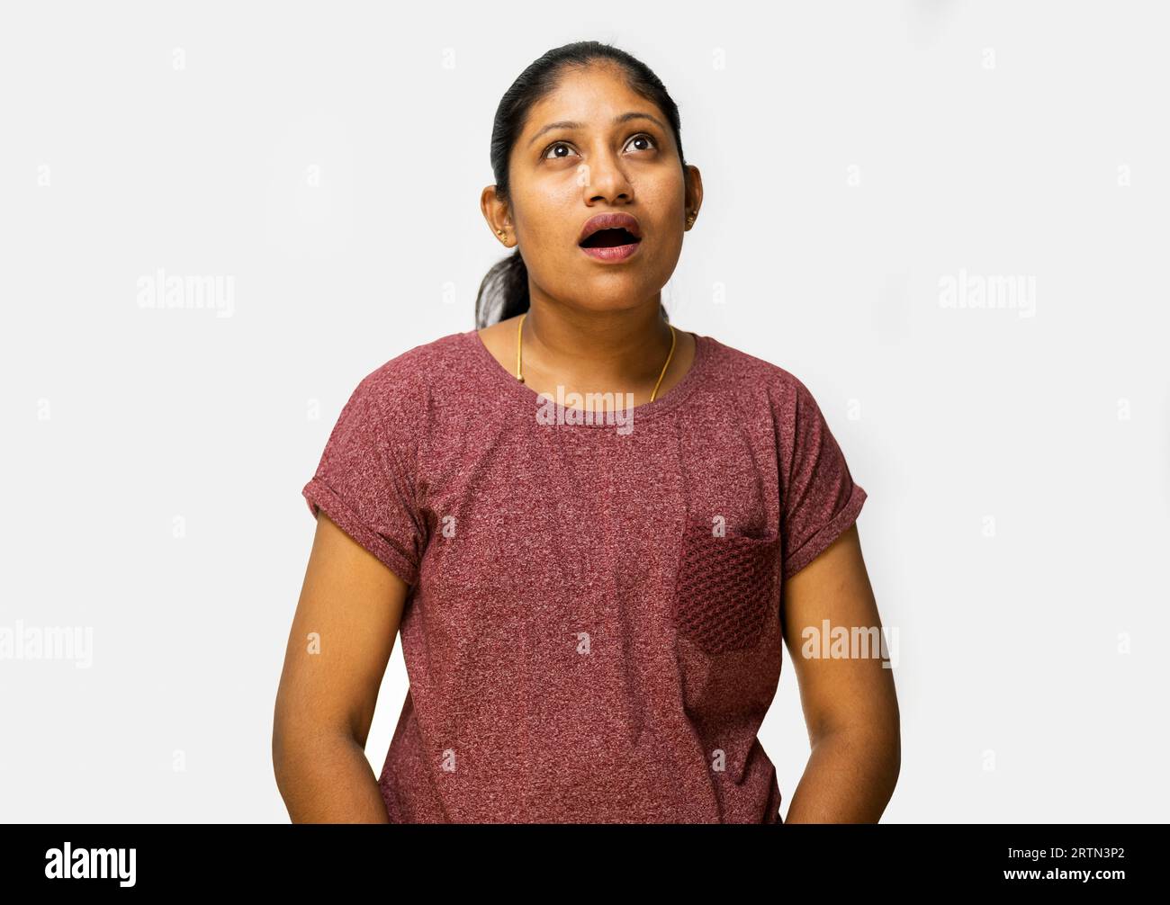 A young woman looks up in surprise, her eyes wide and her mouth agape ...