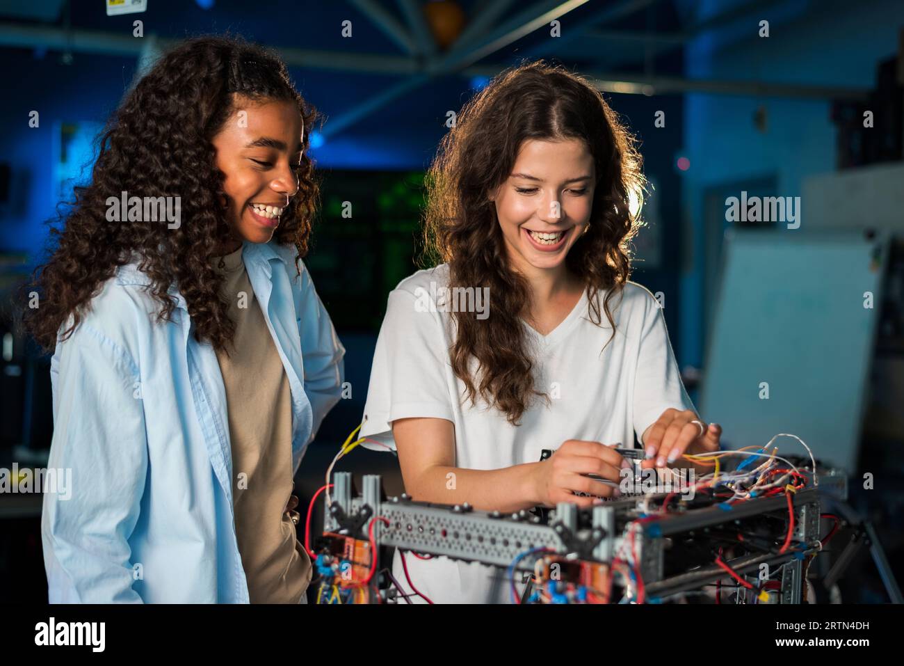 Two young women doing experiments in robotics in a laboratory. Robot on ...
