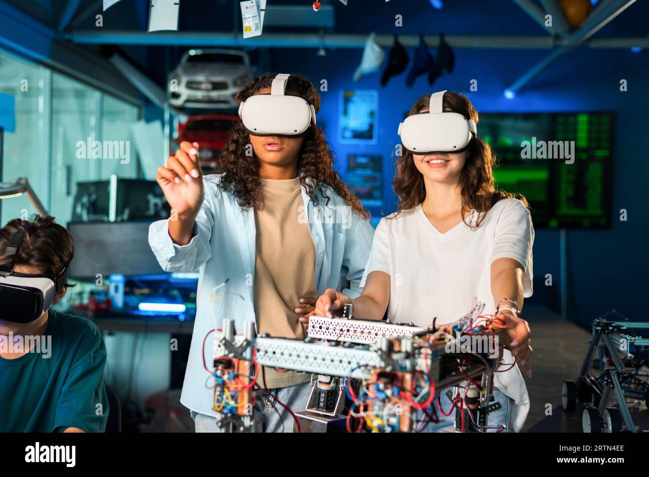Two young women in VR glasses doing experiments in robotics in a ...
