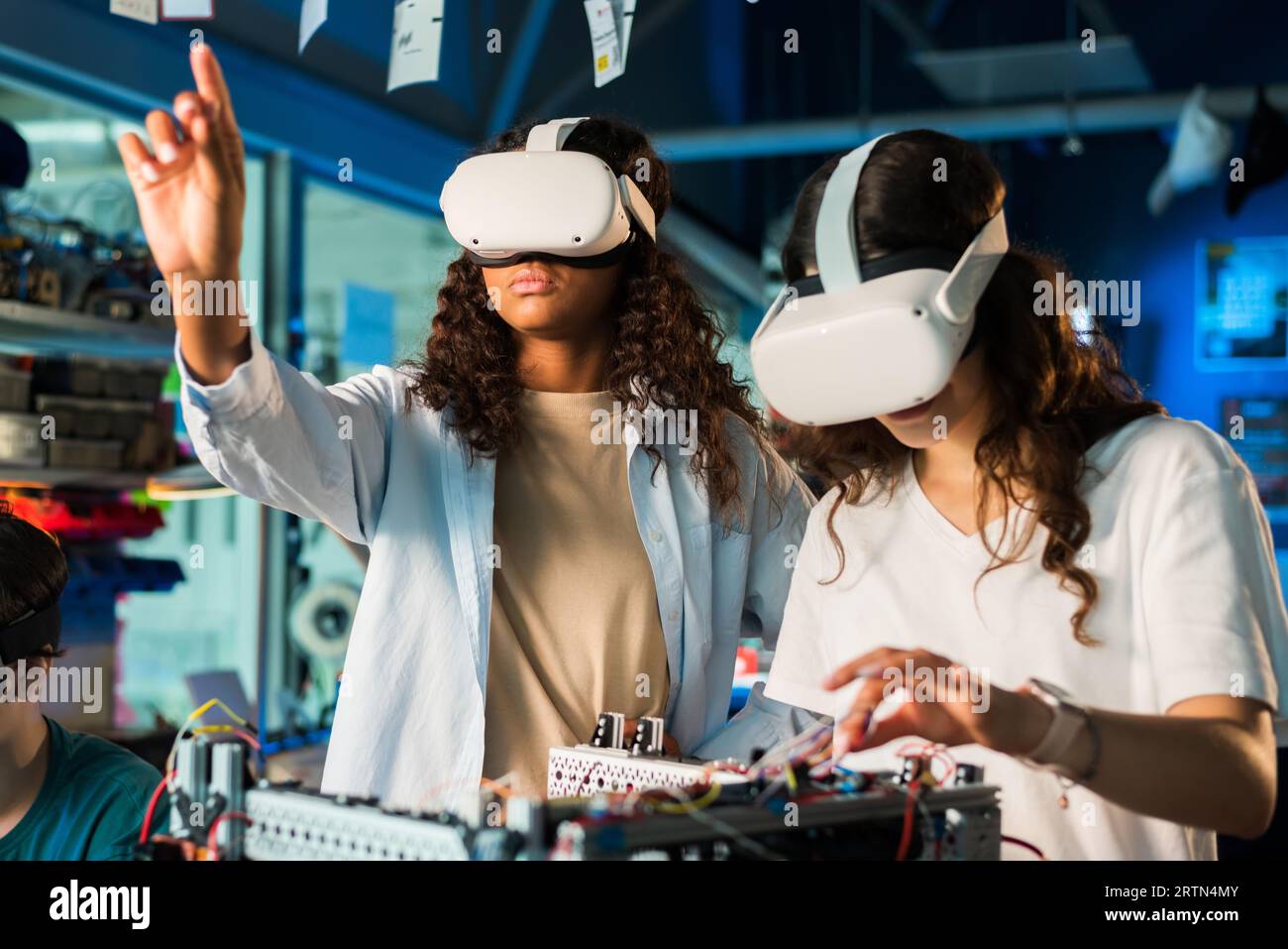 Two young women in VR glasses doing experiments in robotics in a ...