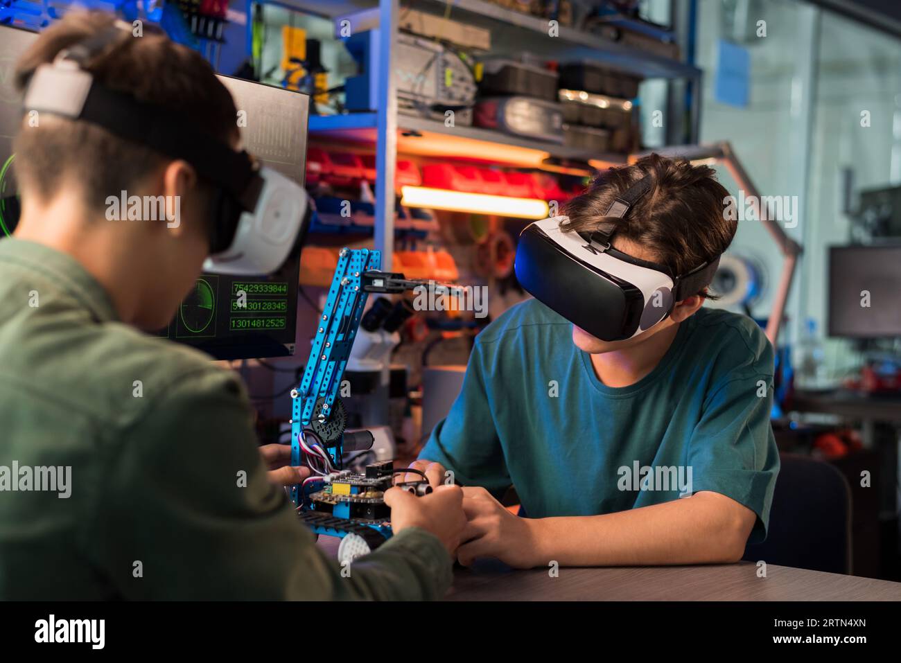 Two young men in VR glasses doing experiments in robotics in a ...