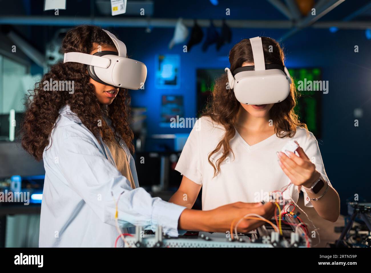 Two young women in VR glasses doing experiments in robotics in a ...