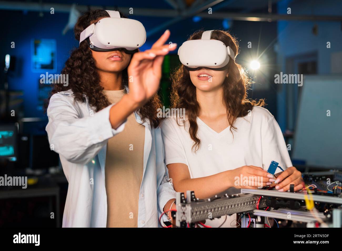 Two young women in VR glasses doing experiments in robotics in a ...