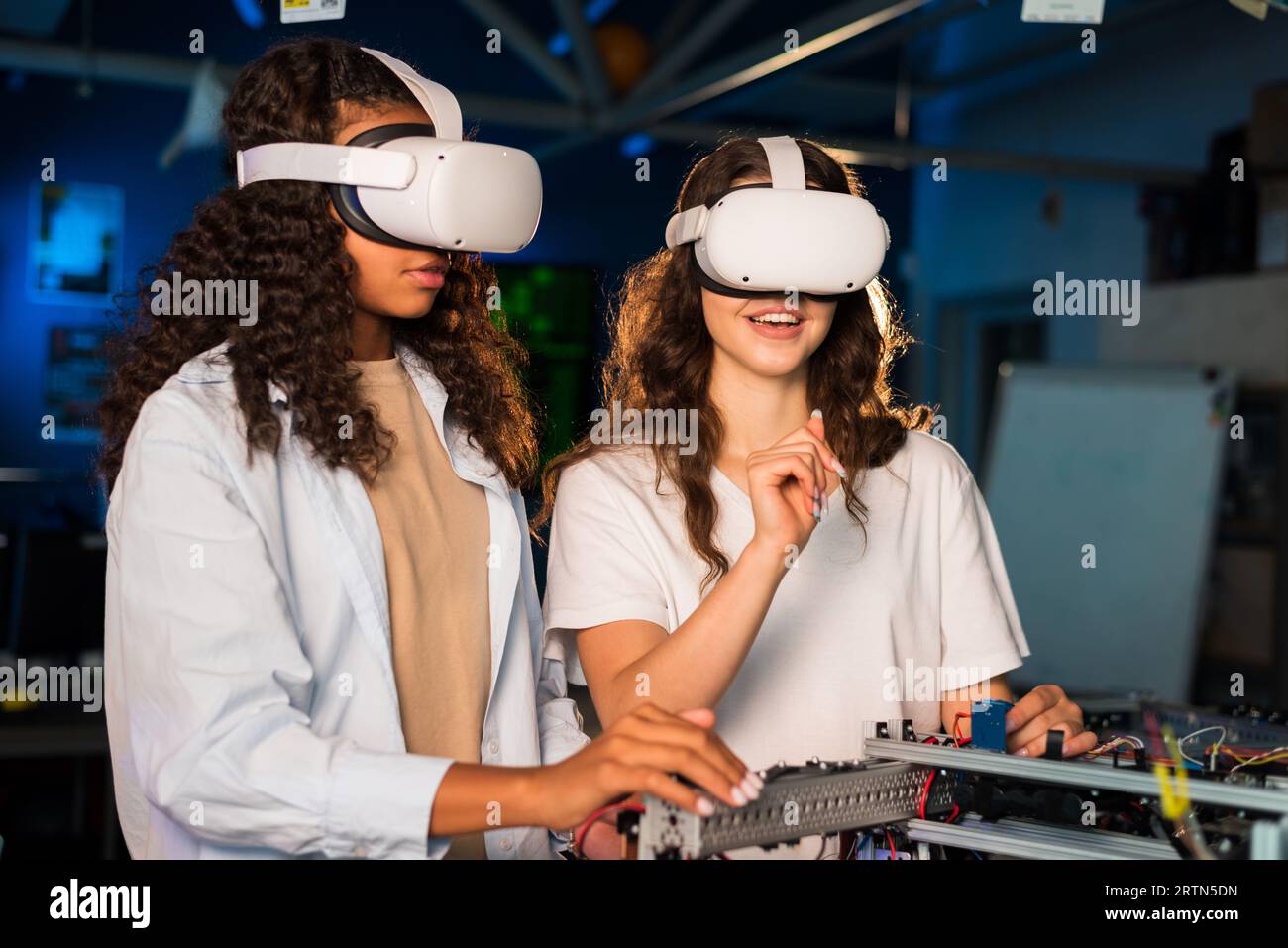 Two young women in VR glasses doing experiments in robotics in a ...