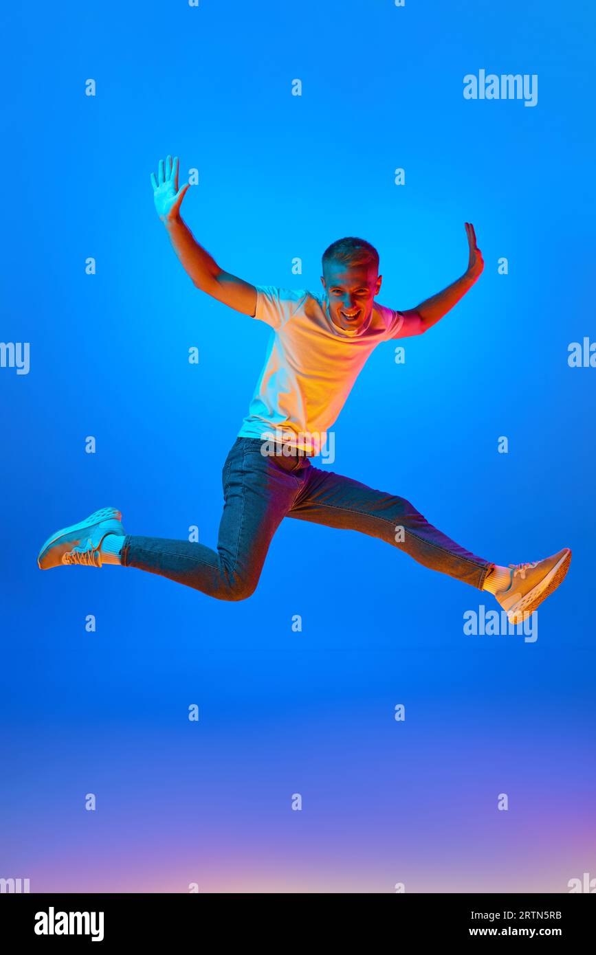 Neon light portrait of victorious delighted jumping man raising hands ...