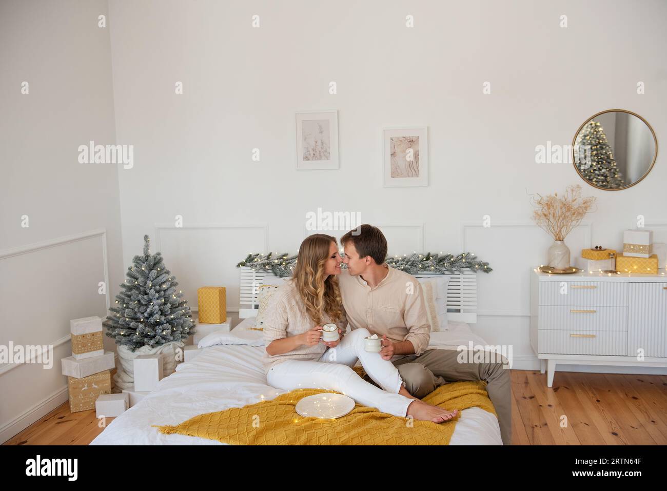 Cute Cheerful Couple Cuddling On Bed With Yellow Blanket On Christmas
