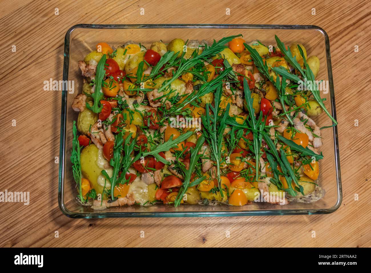 Baked potatoes, meat and vegetables covered in rocket Stock Photo - Alamy