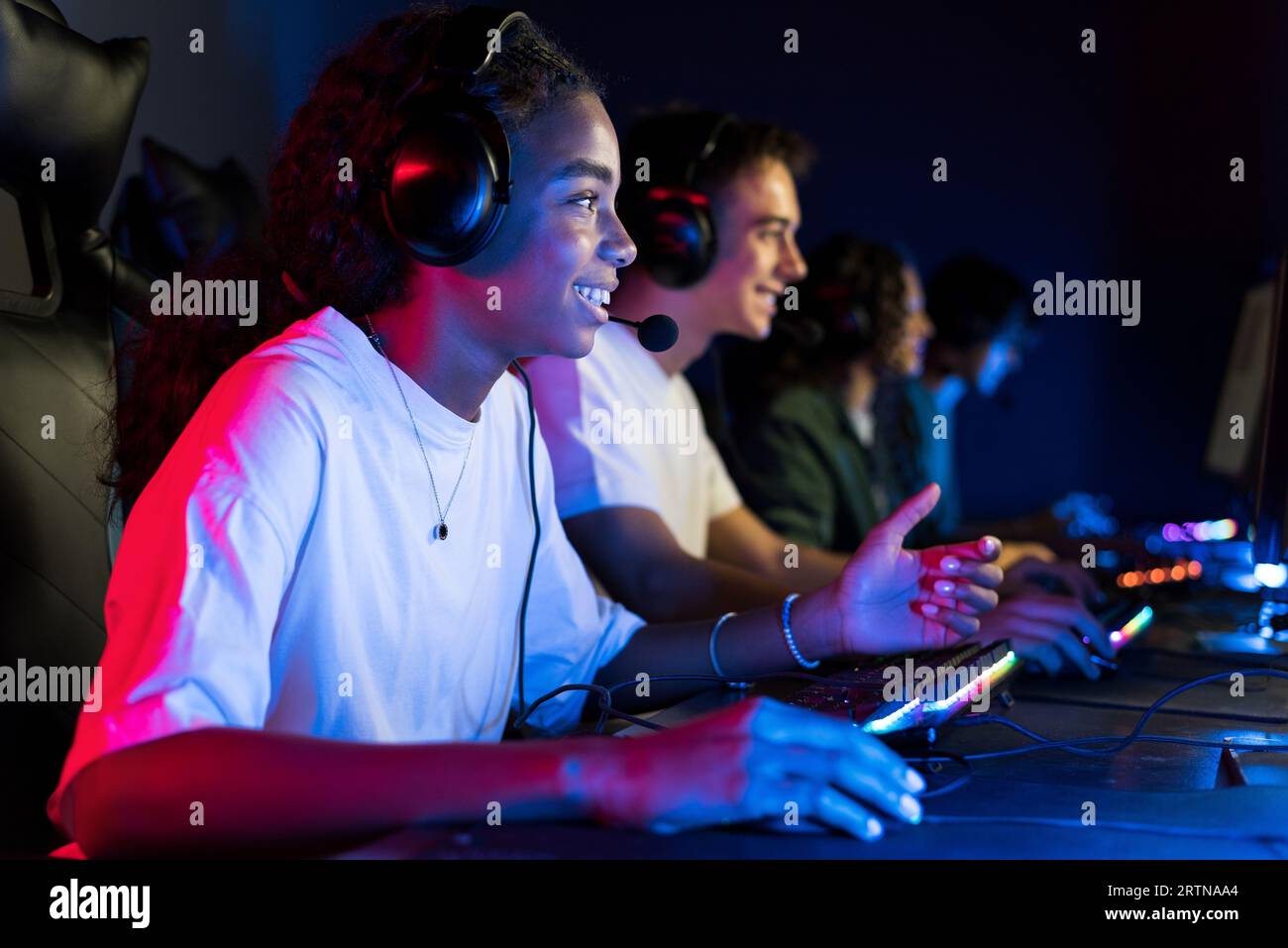 Multiracial group of teens in headsets playing video games in video ...