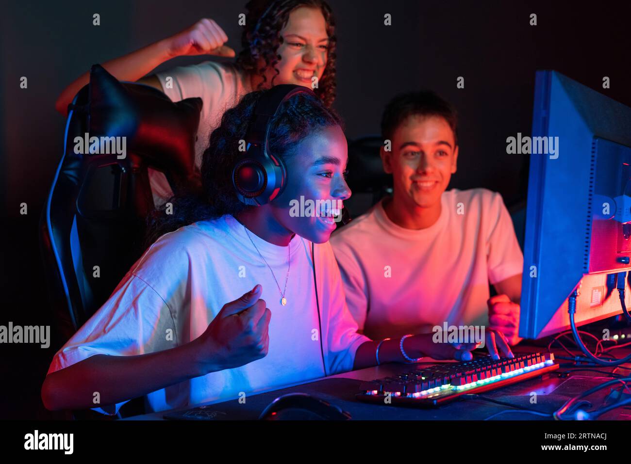 Group of multiracial teens playing video games in video game club with ...