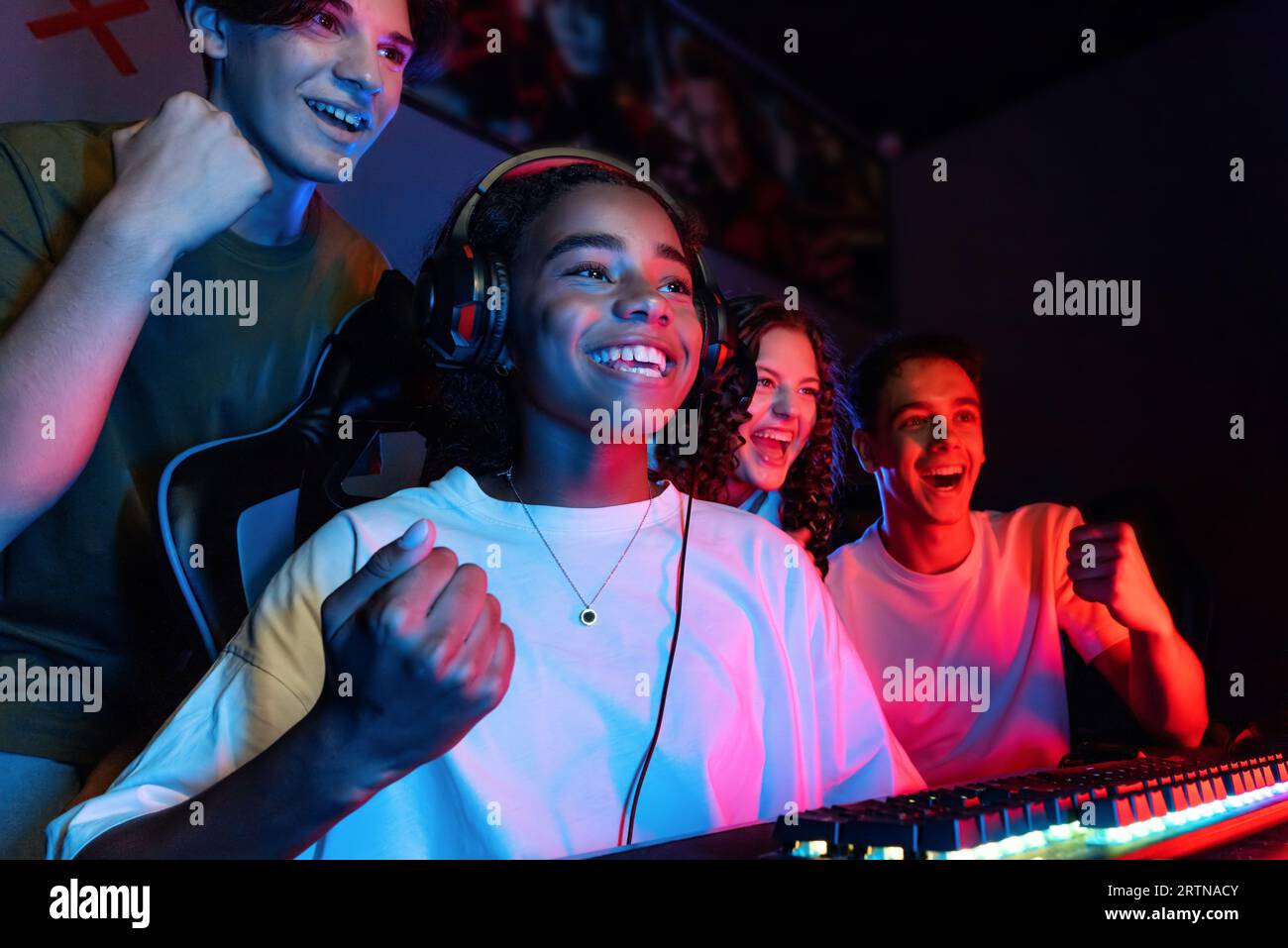 Group of multiracial teens playing video games in video game club with ...