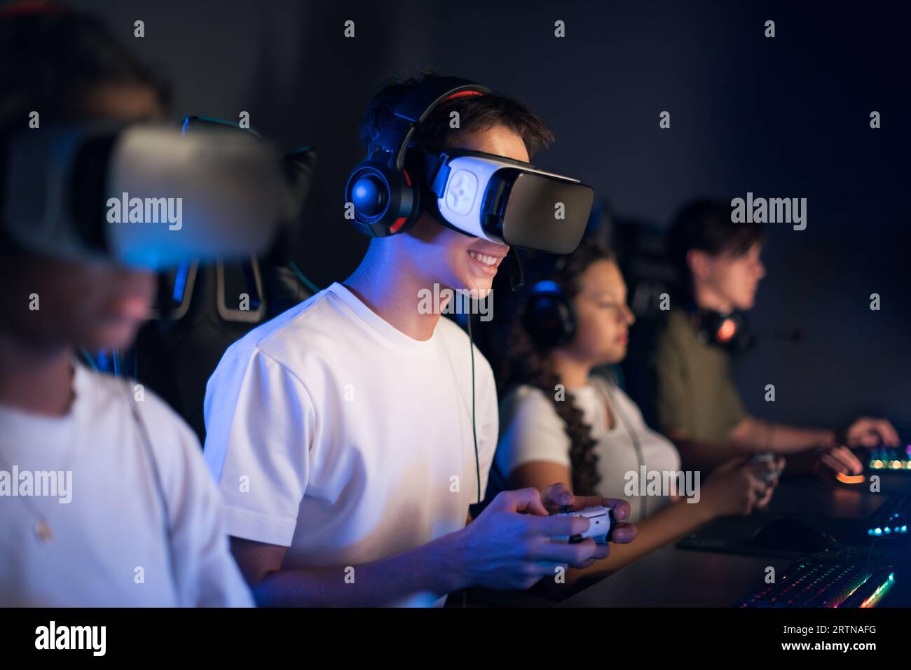 Teen smiling boy in VR headset playing video games in video game club ...