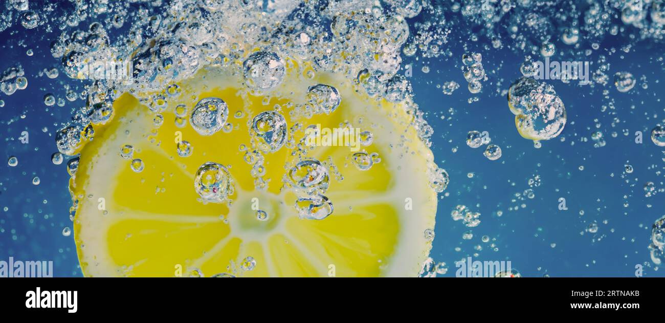 Underwater lemon slice in soda water or lemonade with bubbles. Refreshing soda tonic fizzy ...