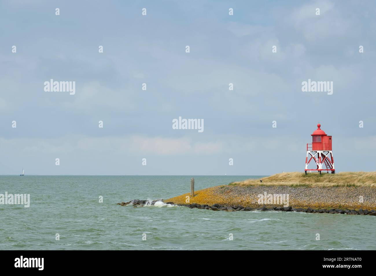 Red cast iron beacon on a pier at the start of Stavoren harbor on a ...