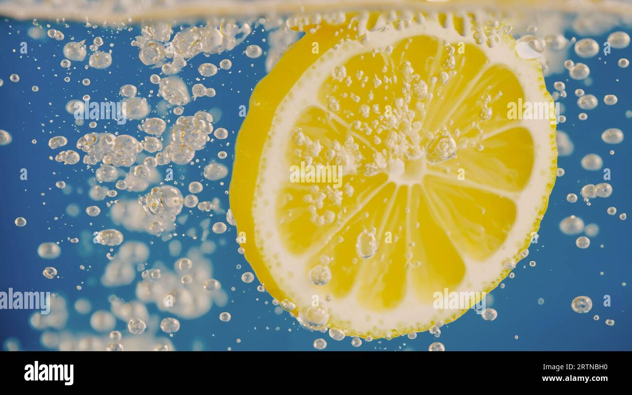 Underwater lemon slice in soda water or lemonade with bubbles. Refreshing soda tonic fizzy ...