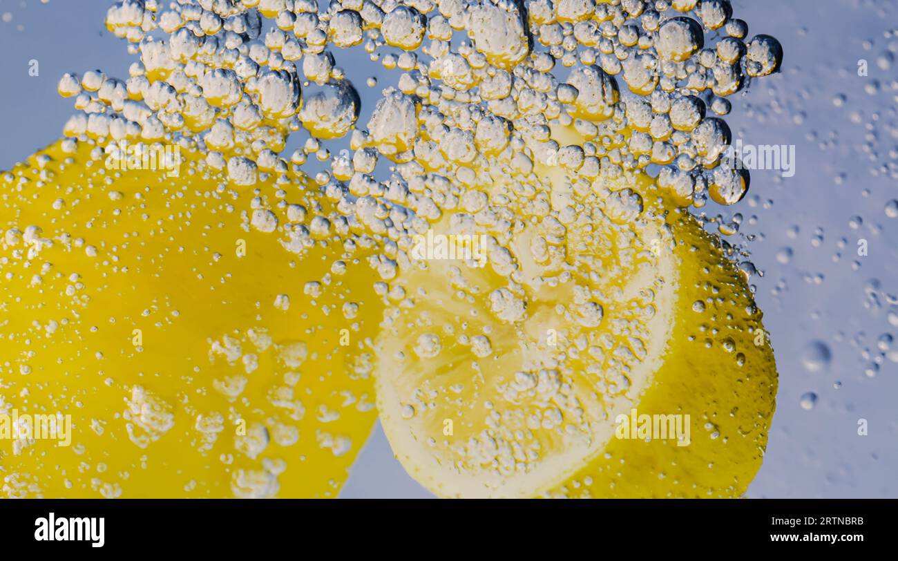 Underwater lemon slice in soda water or lemonade with bubbles. Refreshing soda tonic fizzy ...