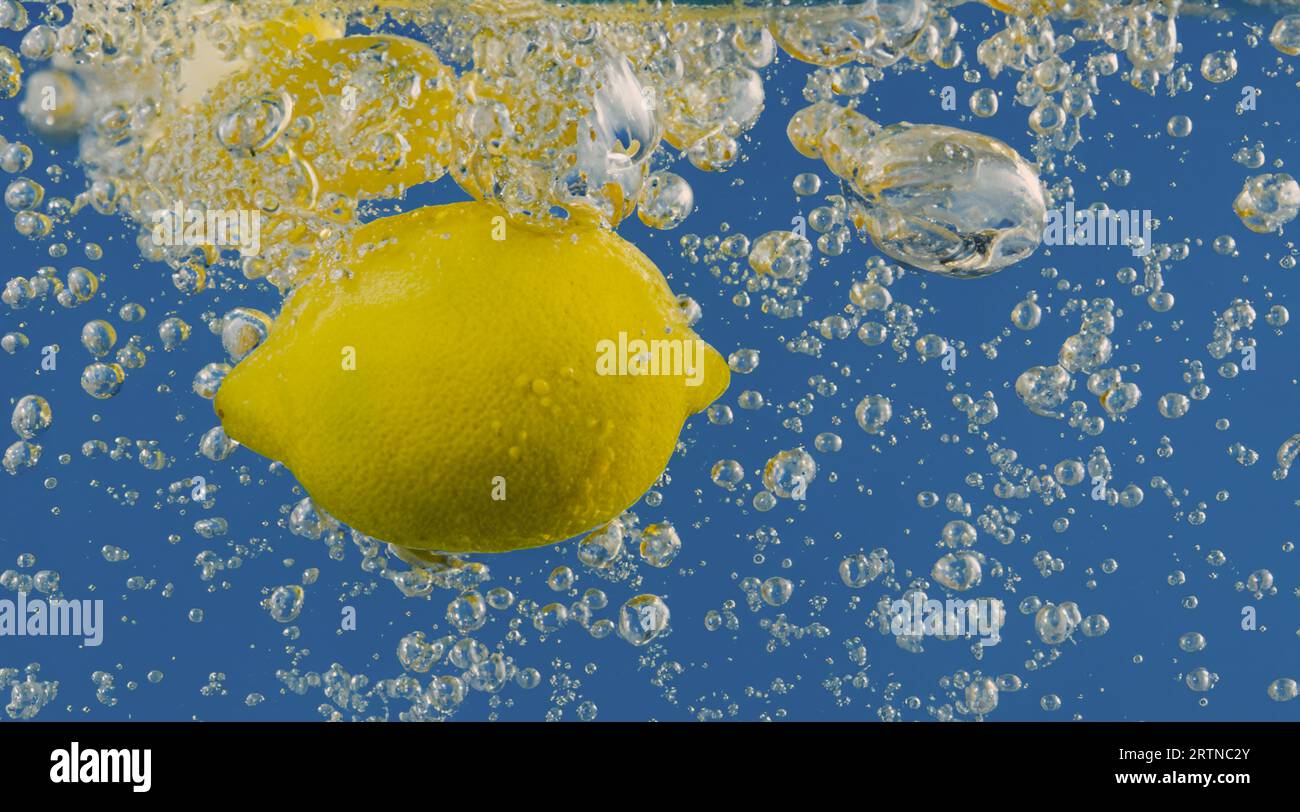 Underwater lemon slice in soda water or lemonade with bubbles. Refreshing soda tonic fizzy ...