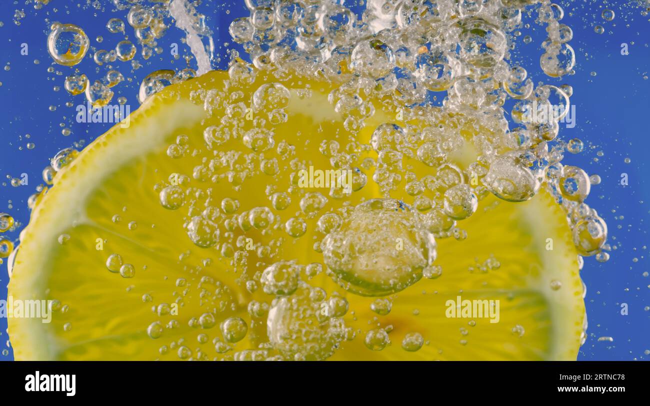Underwater lemon slice in soda water or lemonade with bubbles. Refreshing soda tonic fizzy ...