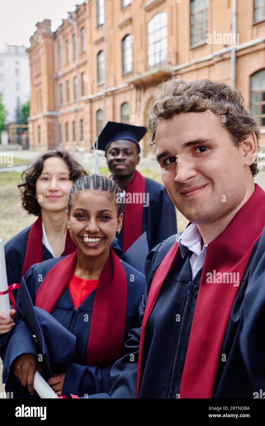 Vertical image of students in graduation gowns making selfie portrait ...