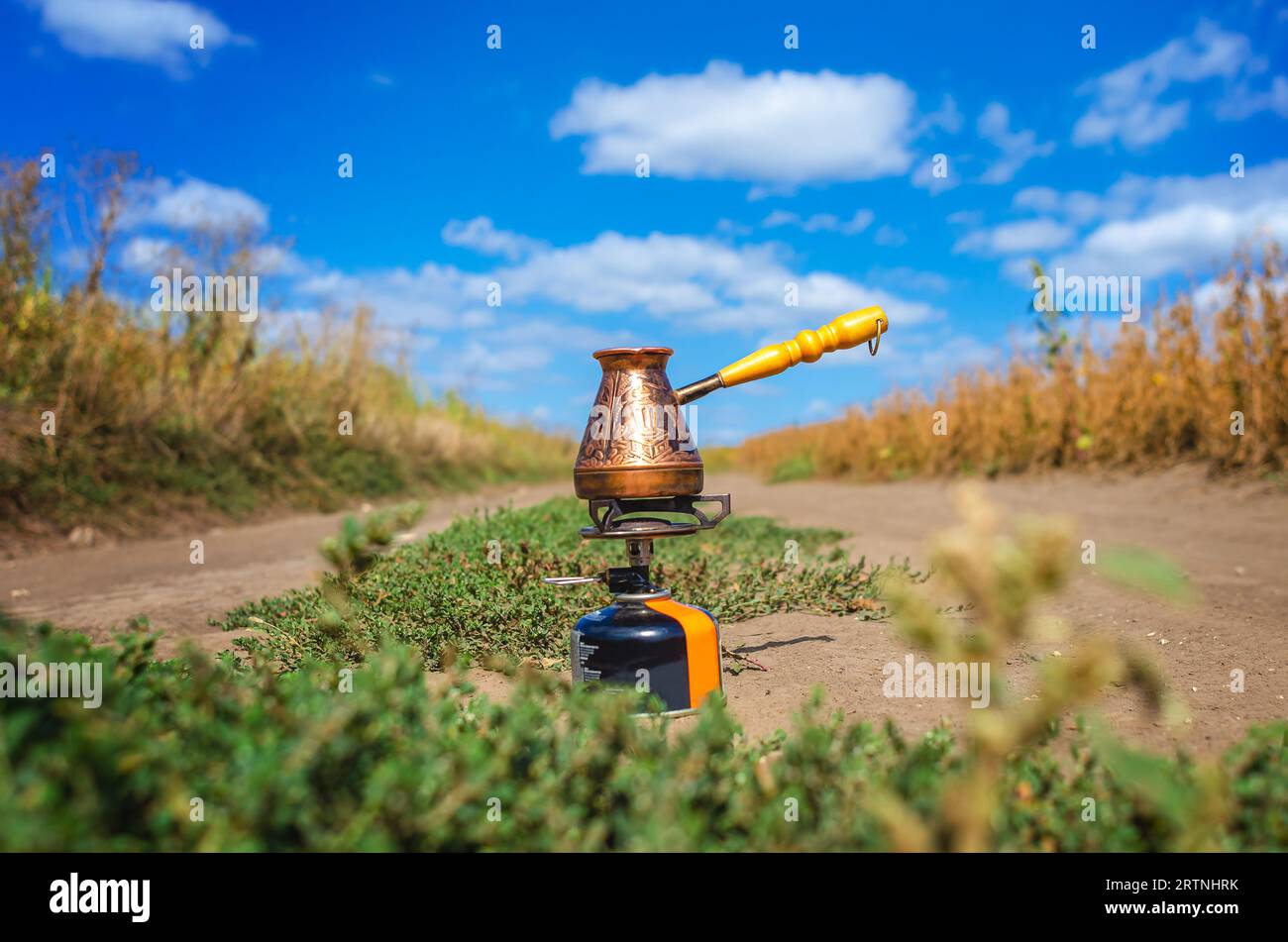 Copper cezve on a gas burner outdoors under blue sky. Coffee in nature ...