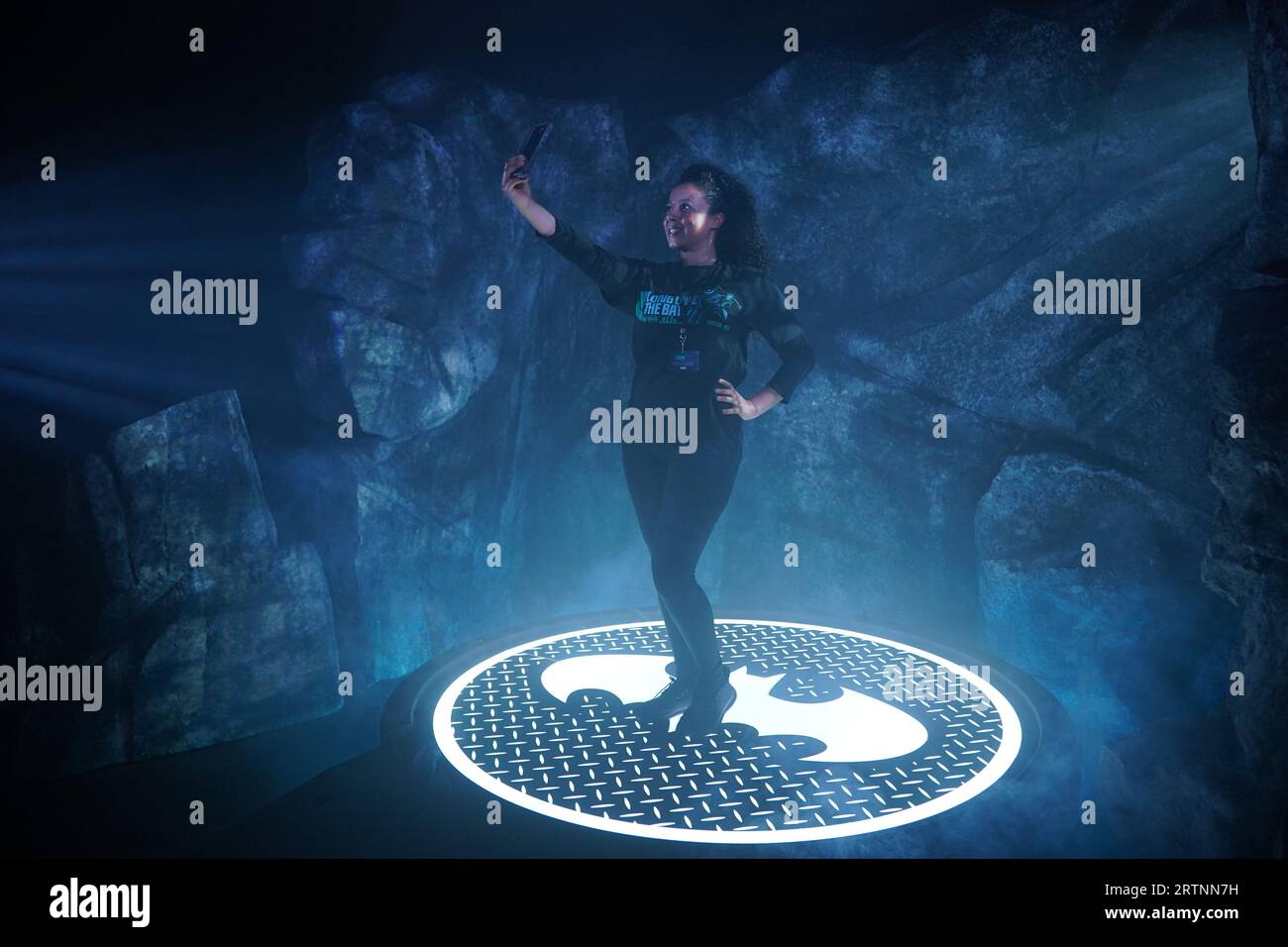 A woman takes a selfie in the Batcave at the DC Comics and Warner Bros ...