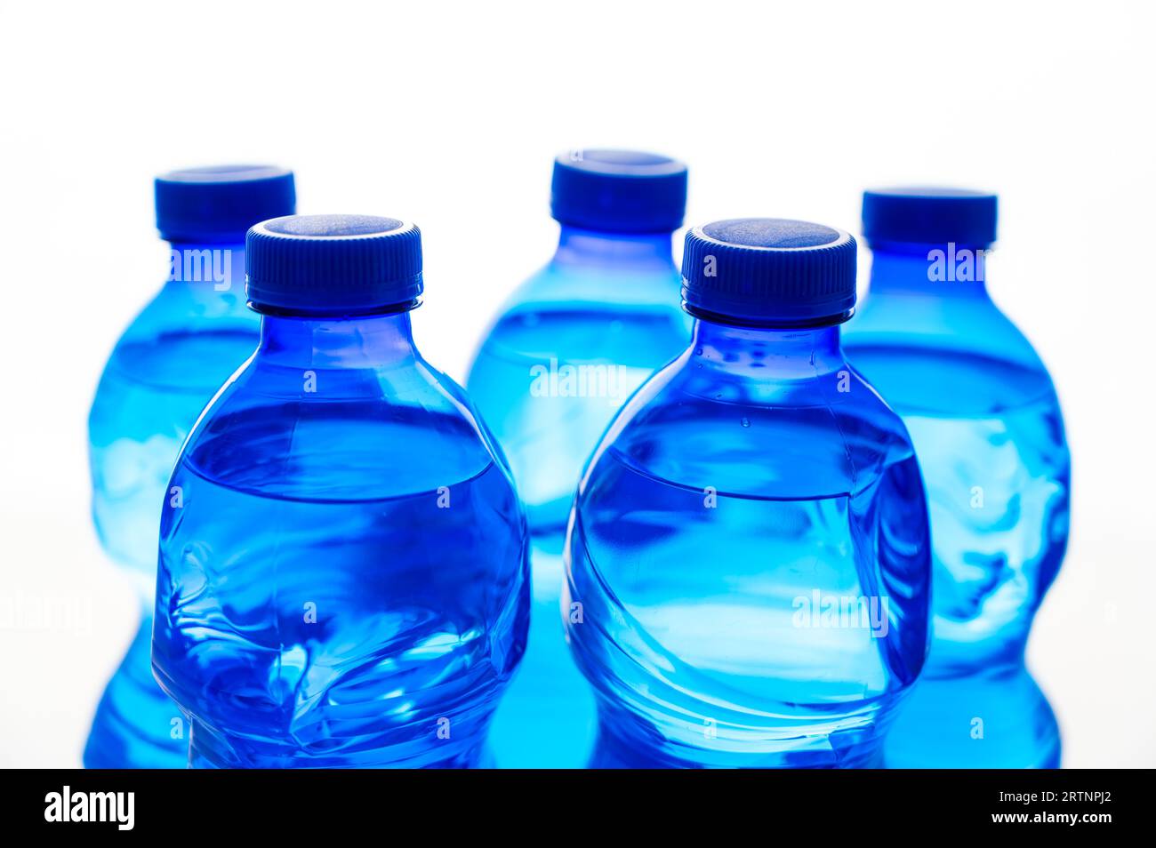Transparent blue plastic bottles containing water, next to each other ...