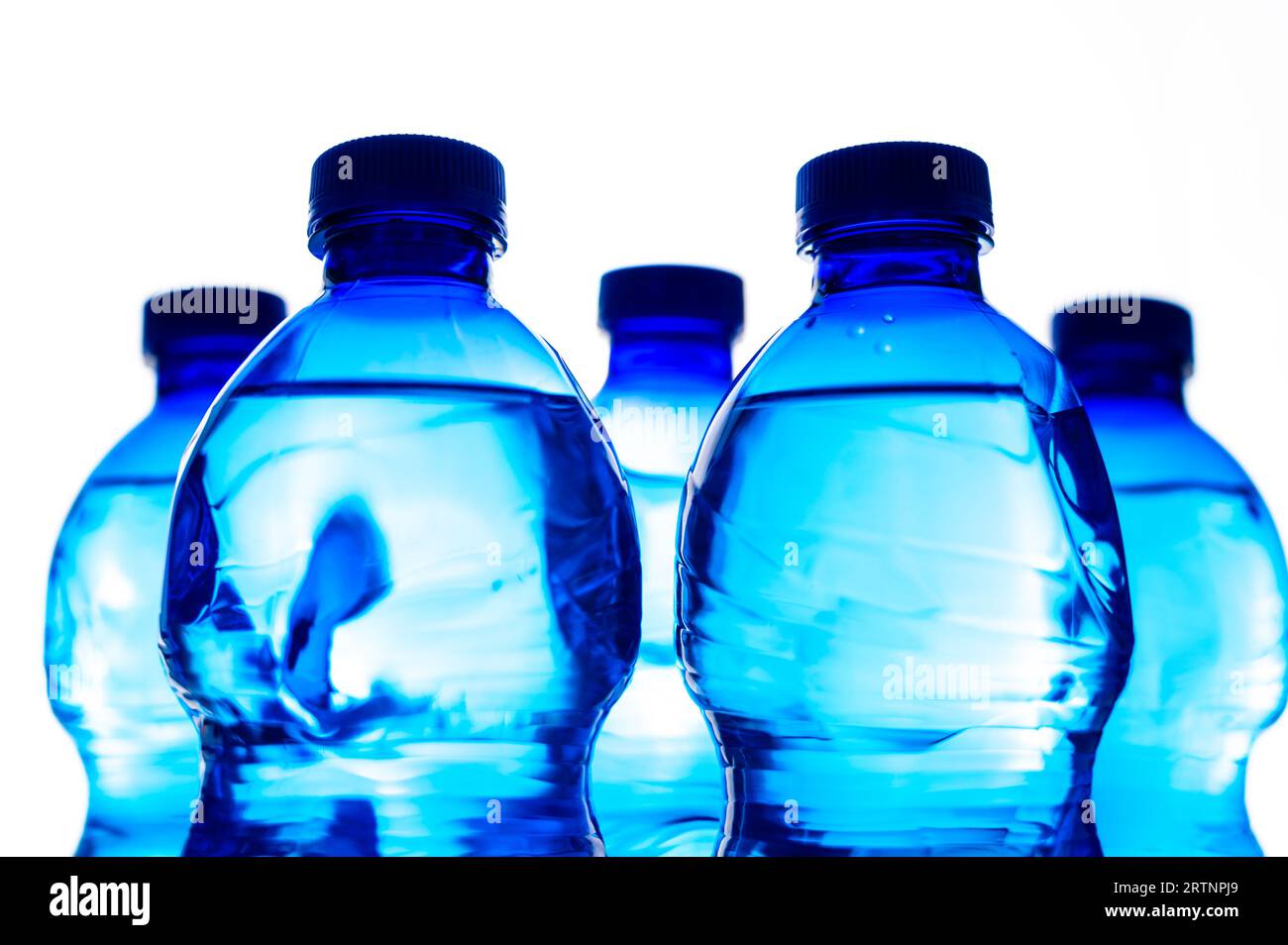 Transparent blue plastic bottles containing water, next to each other ...