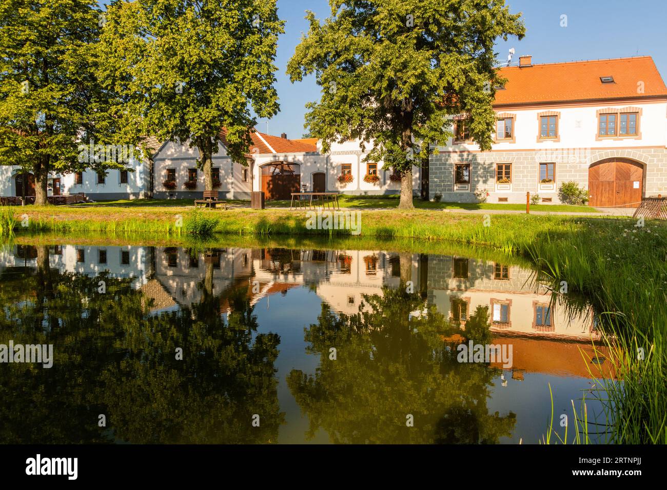 Pond and traditional houses of rural baroque style in Holasovice ...