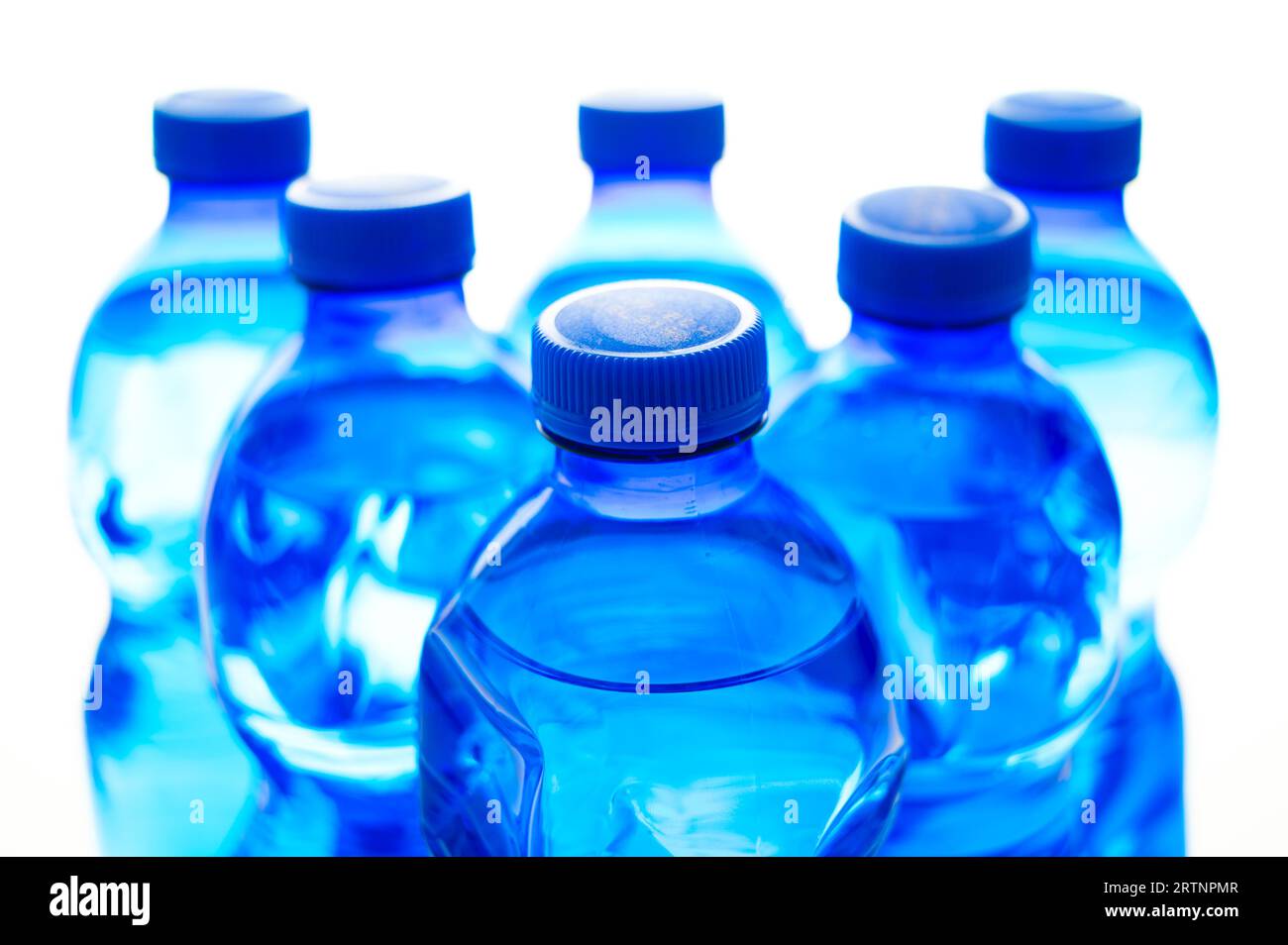 Transparent blue plastic bottles containing water, next to each other ...
