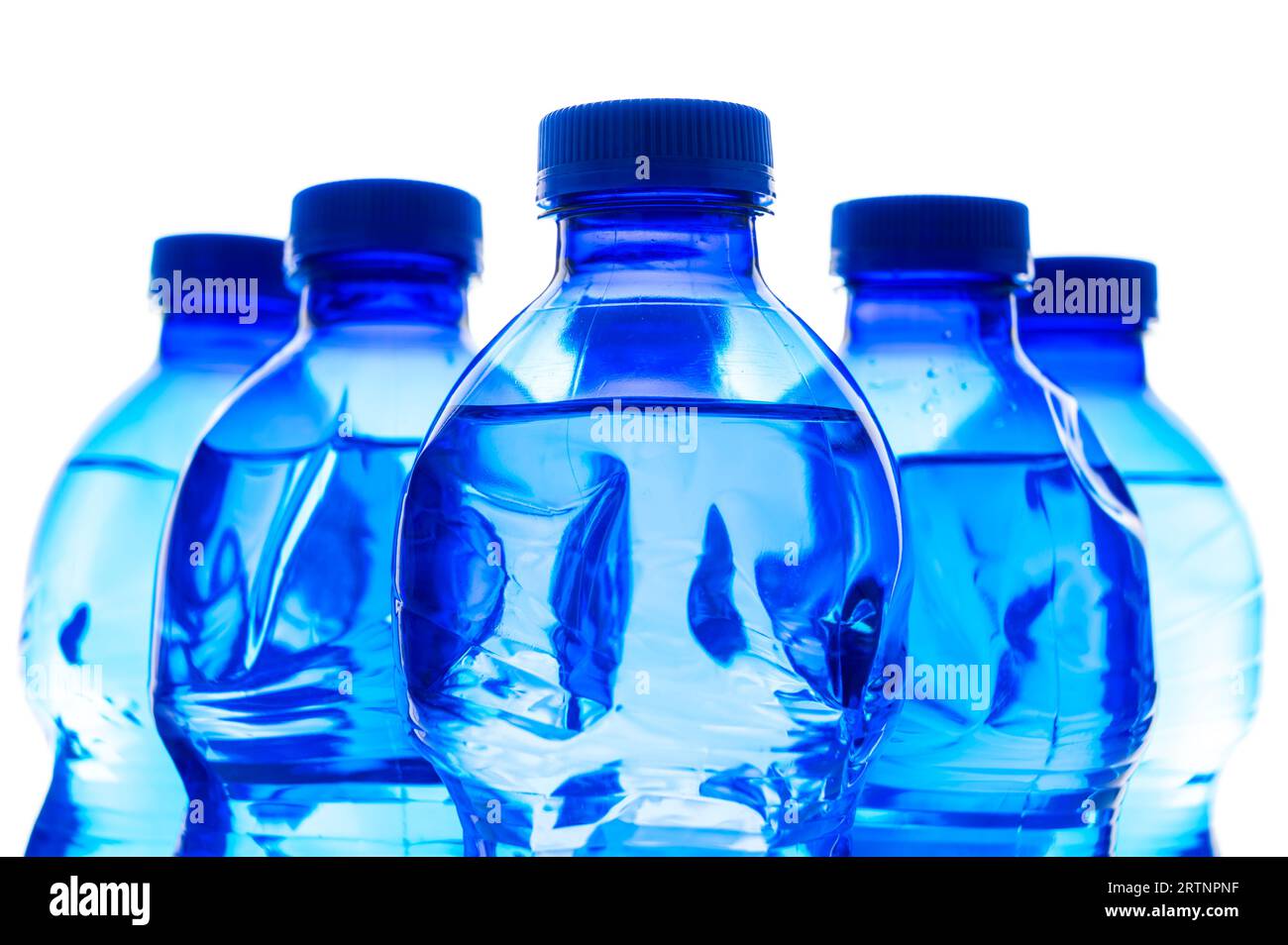Transparent blue plastic bottles containing water, next to each other ...