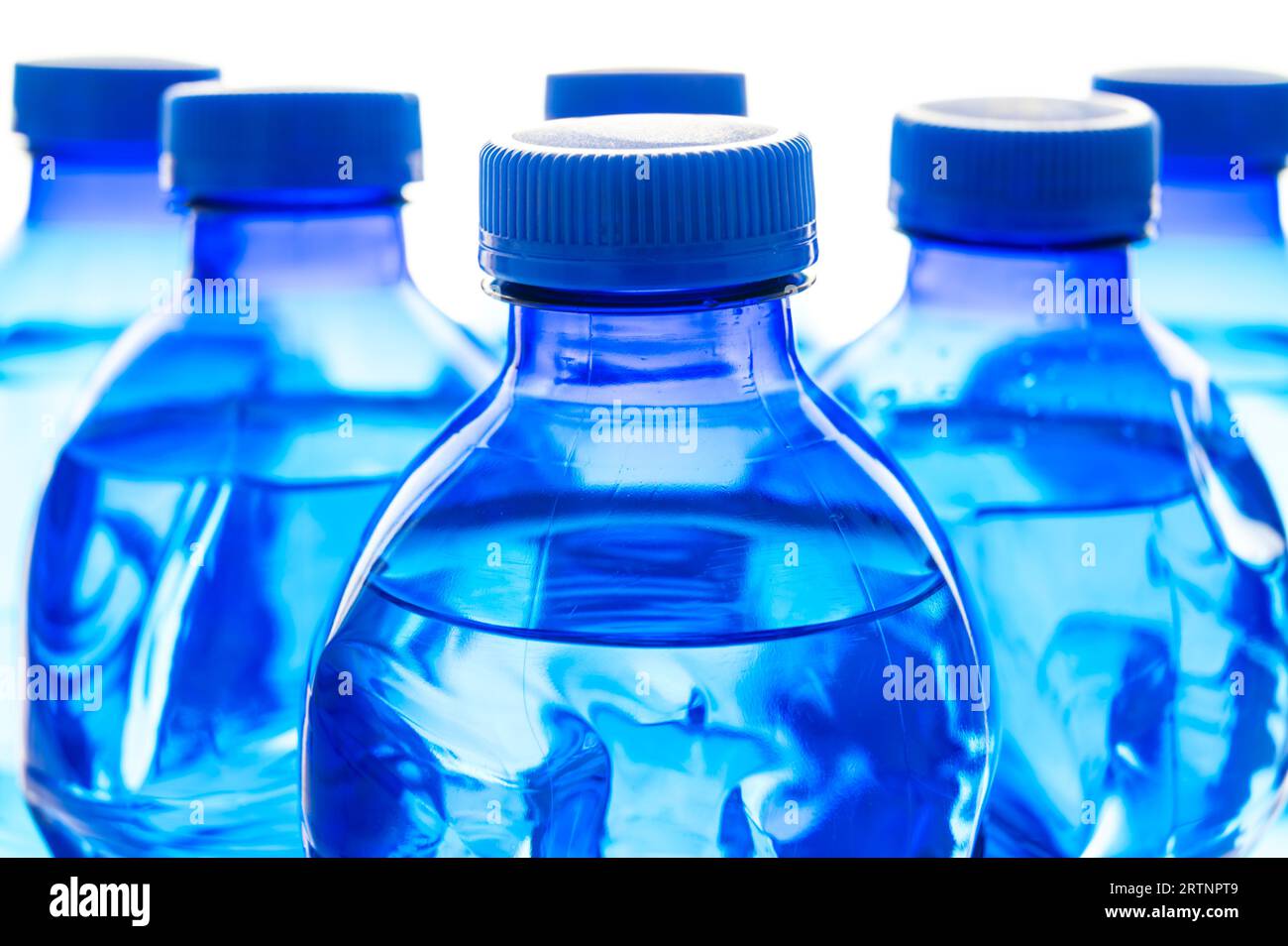 Transparent blue plastic bottles containing water, next to each other ...