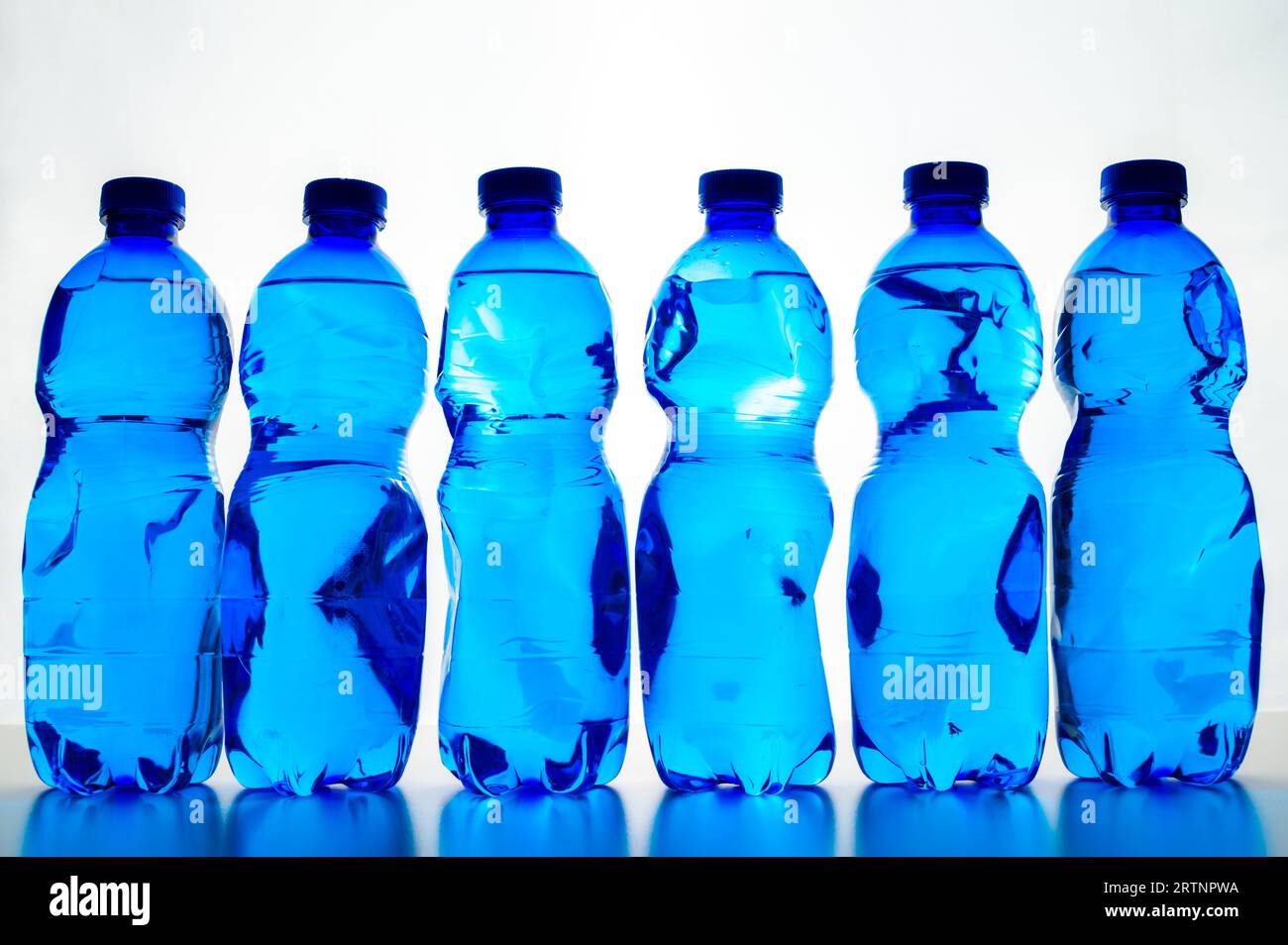 Transparent blue plastic bottles containing water, next to each other ...