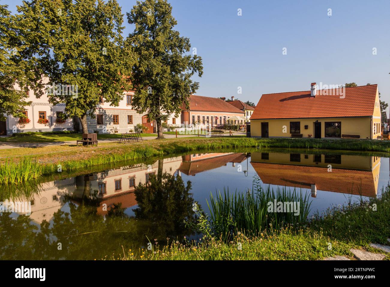 Pond and traditional houses of rural baroque style in Holasovice ...