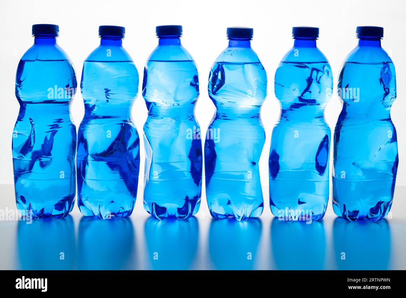 Transparent blue plastic bottles containing water, next to each other ...