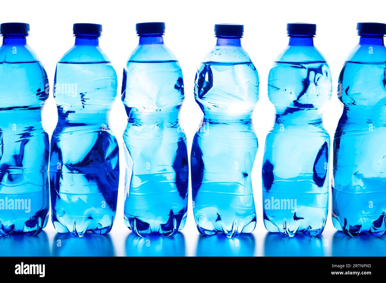 Transparent blue plastic bottles containing water, next to each other ...