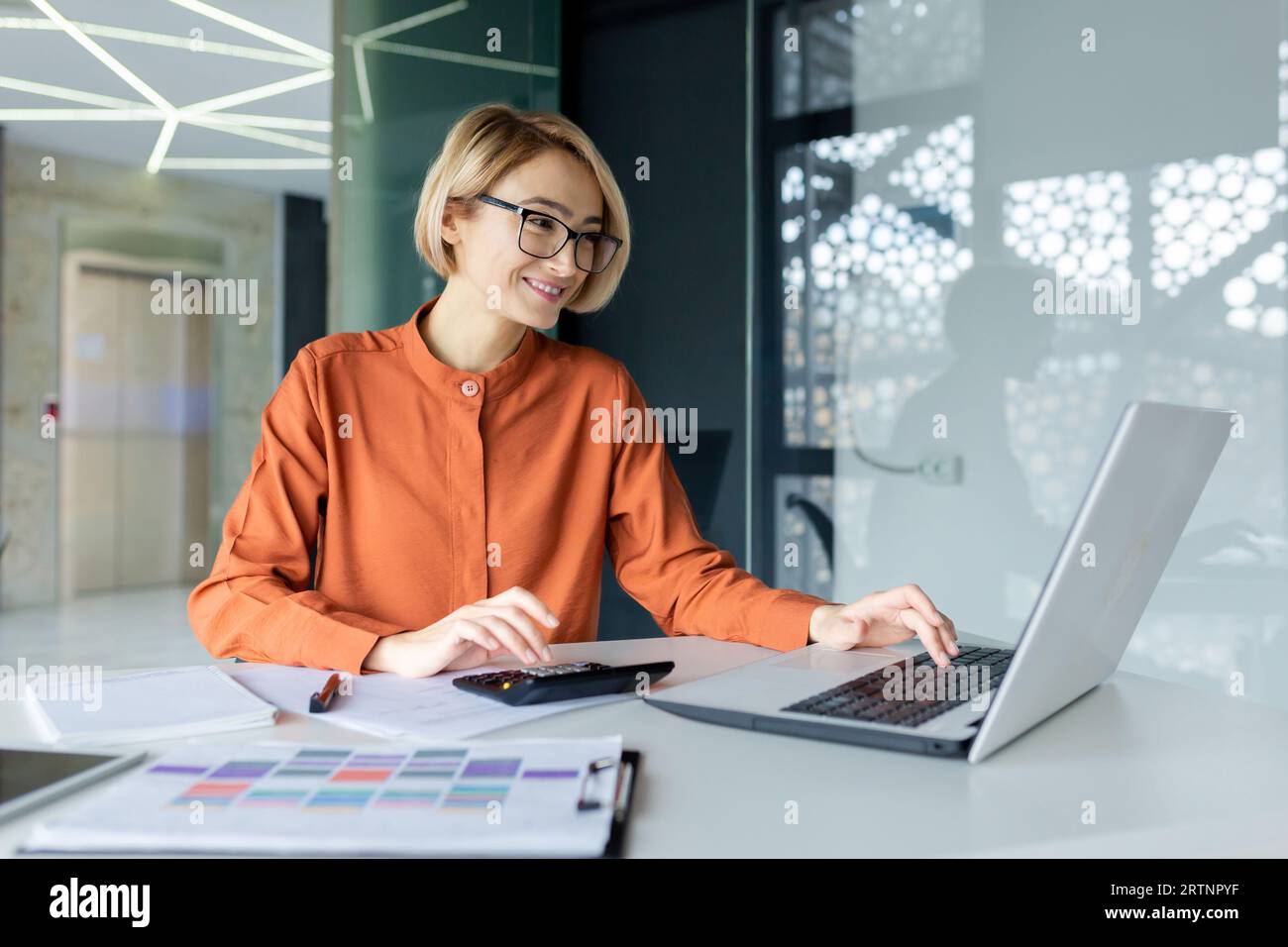 Young female financier with calculator working inside office at ...