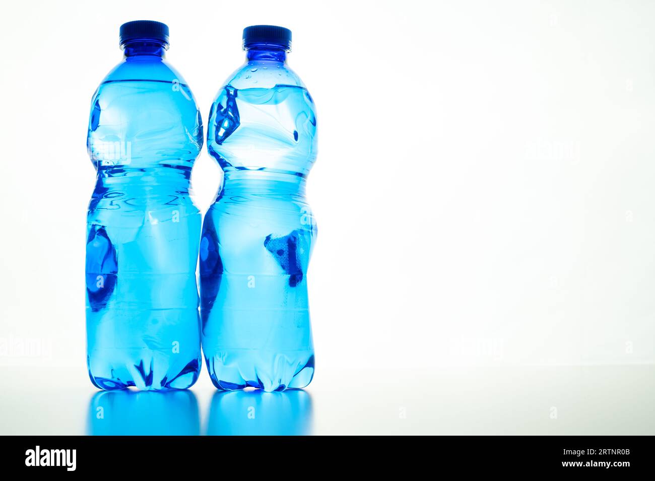 Transparent blue plastic bottles containing water, next to each other ...