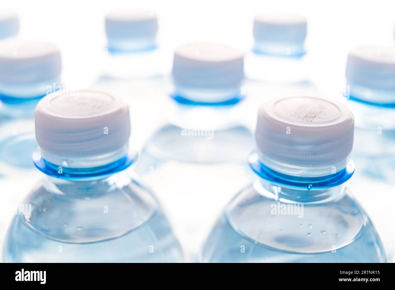 Transparent blue plastic bottles containing water, next to each other ...