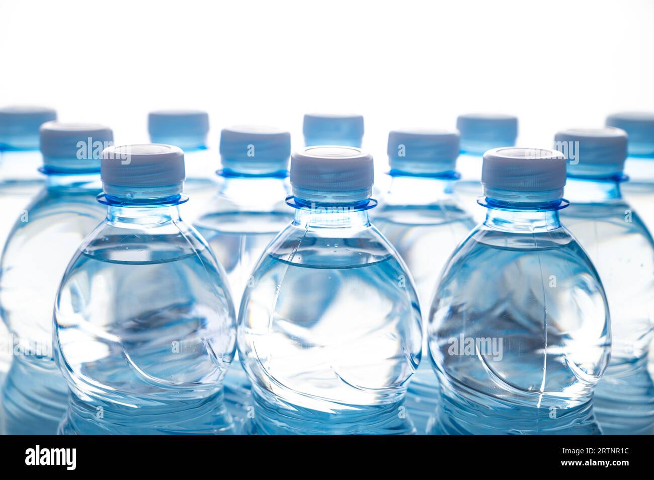 Transparent blue plastic bottles containing water, next to each other ...