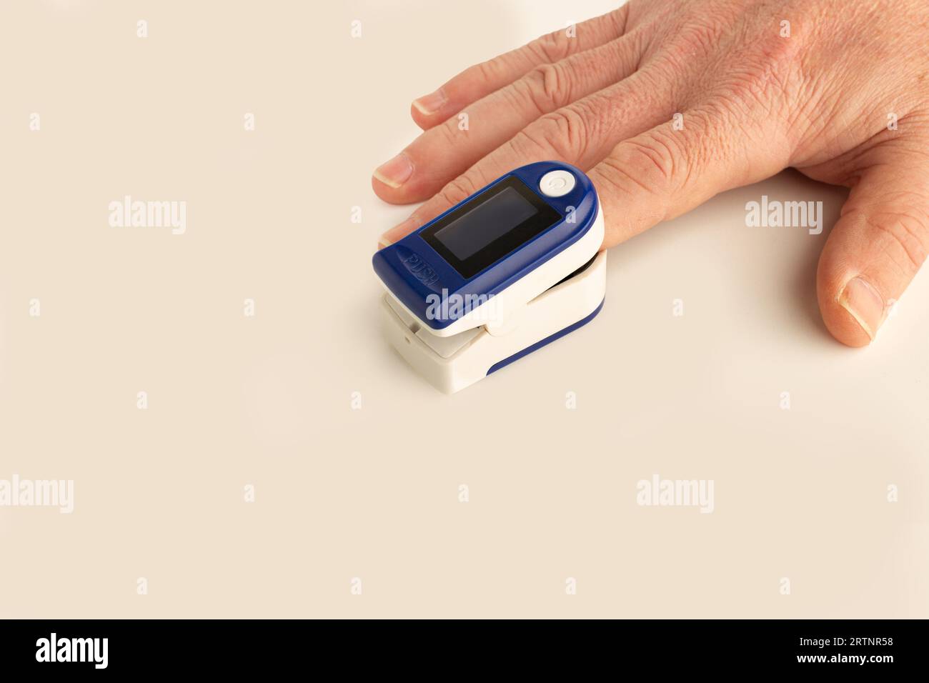 Man using a portable finger heart pulse meter on a white background ...