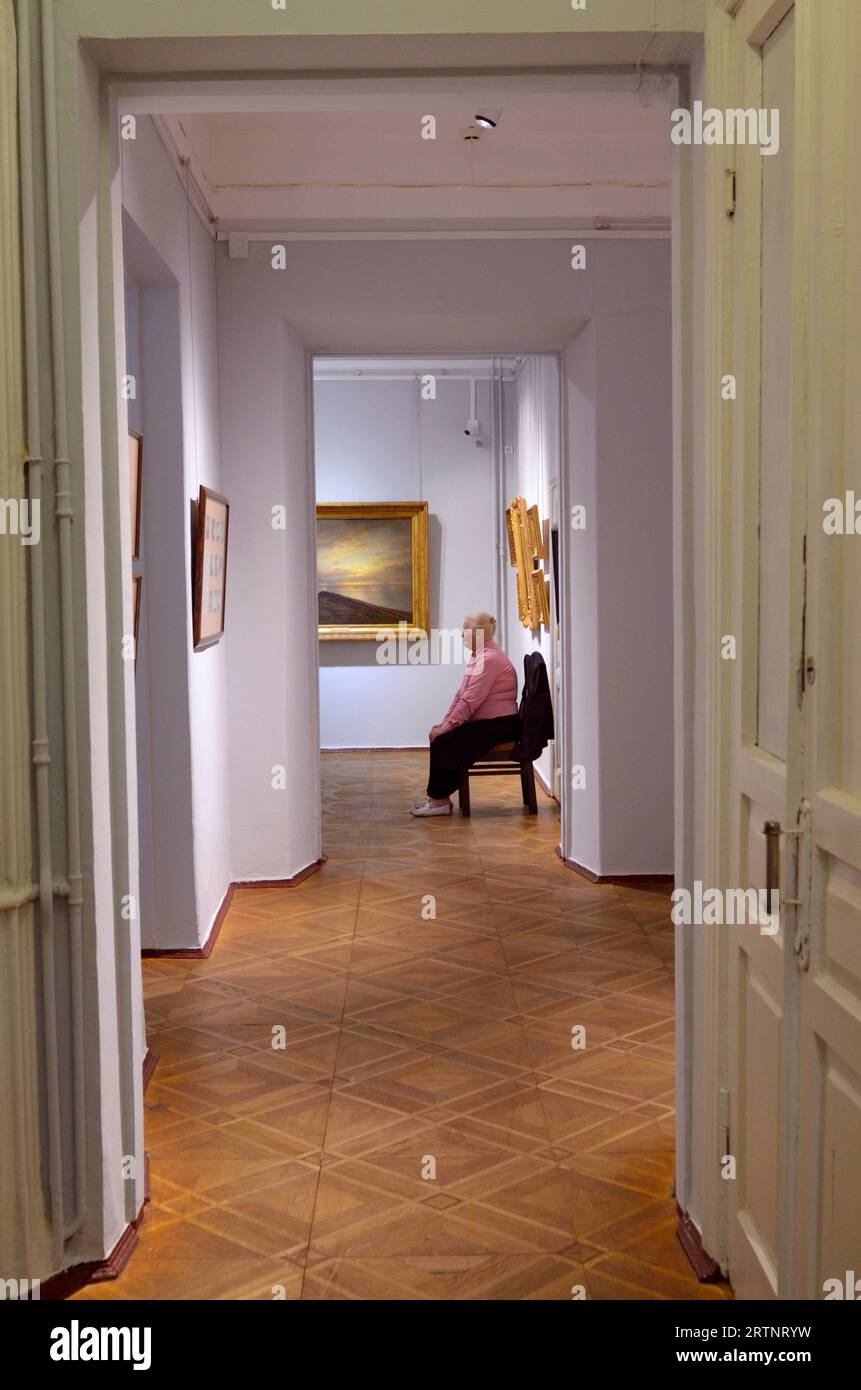 Old woman museum curator sitting on the chair watching an order in ...