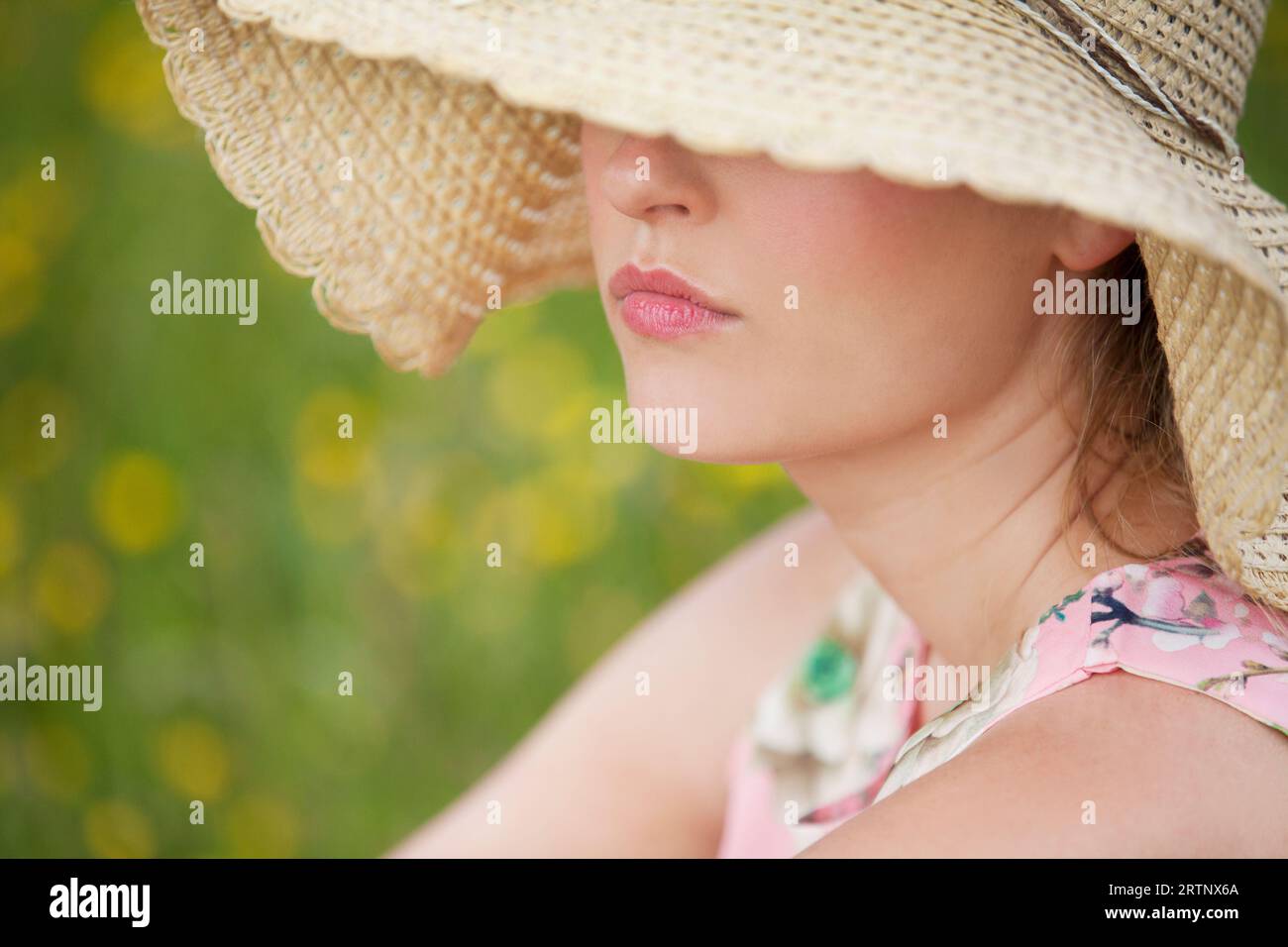 young lady breathing in fresh air in meadow with straw hat covering ...