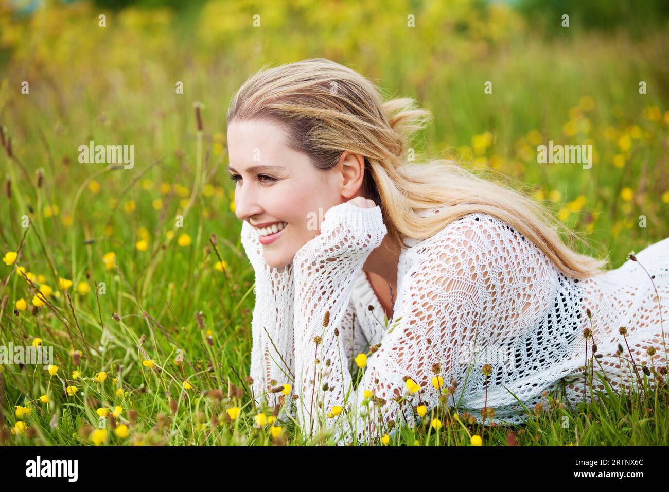 young lady smiling while lying on front in a field Stock Photo - Alamy