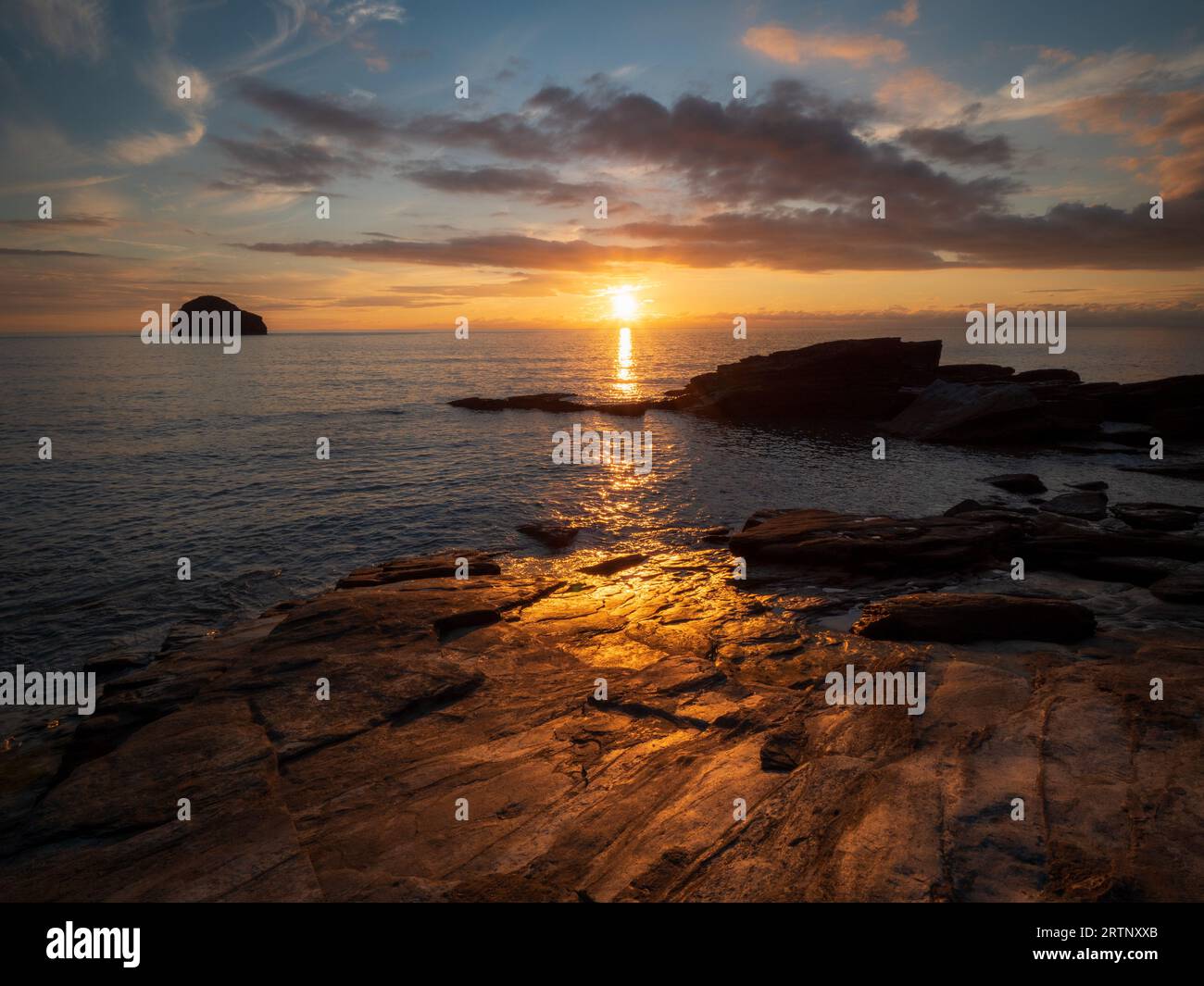 The sun setting beneath the clouds at Trebarwith Strand beach in ...