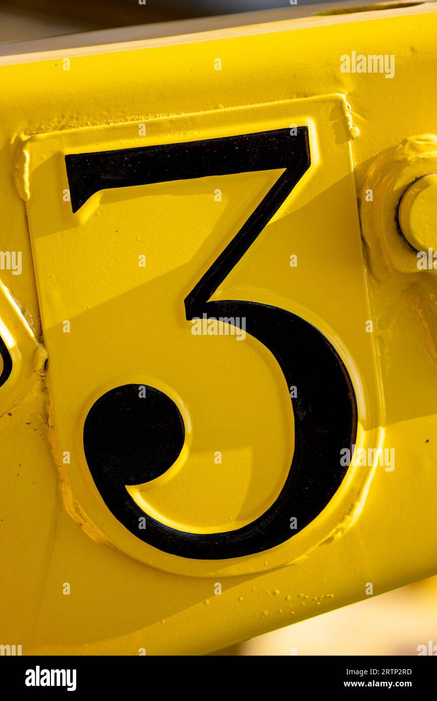 The number three 3 in black old font text on metal yellow background ...